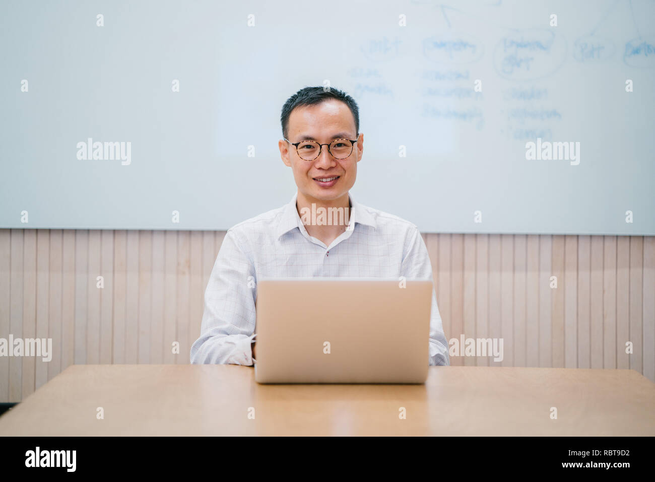 A young Chinese Asian business man is working on his laptop computer in ...