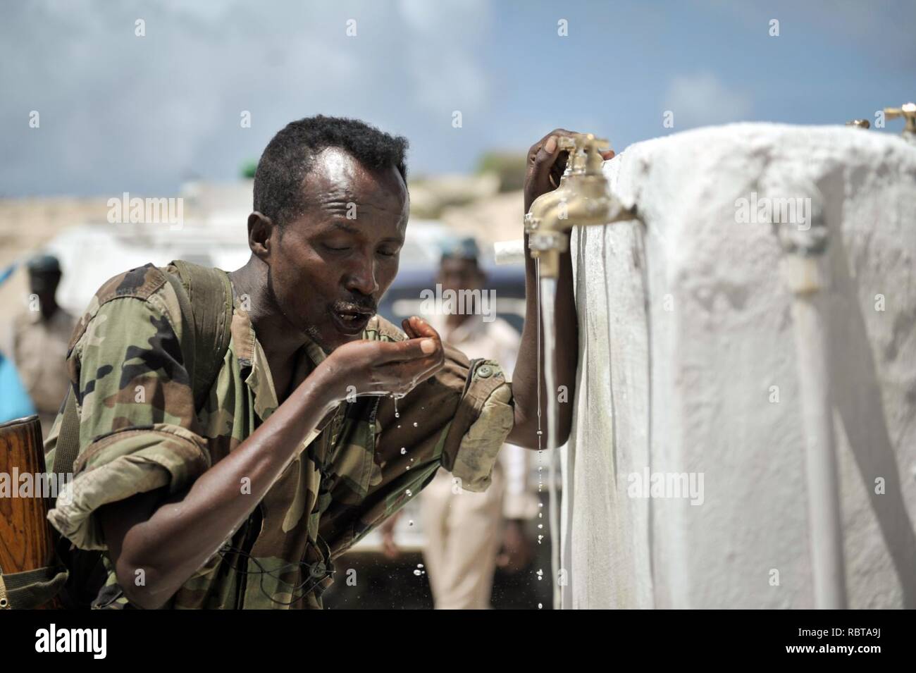 A member of the Somali National Army drinks from a newly opened well ...