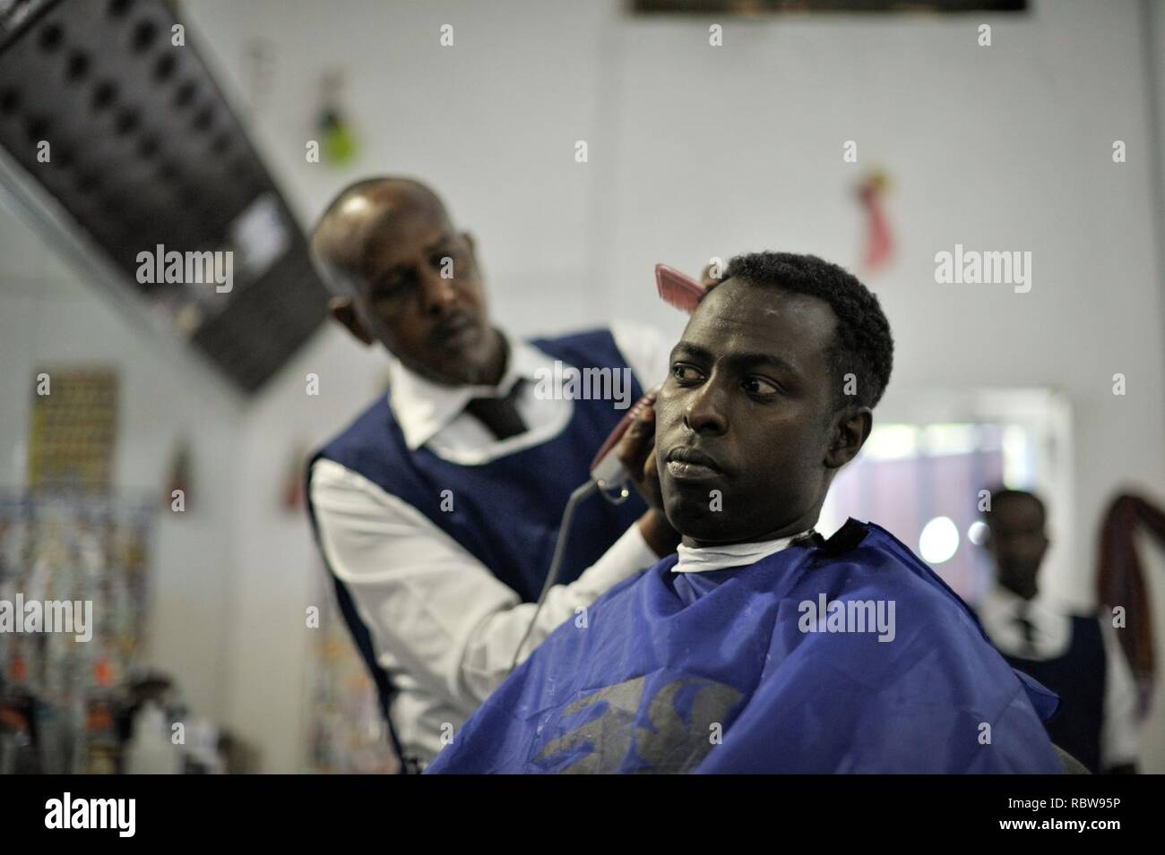A hairdresser gives a haircut at Abdulqadir Abdul's newly opened barber ...