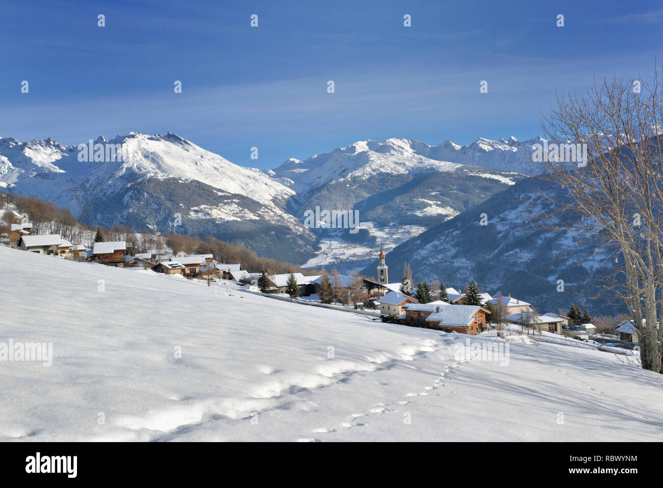 tracks in the snow going to an alpine french village in snowy mountain ...
