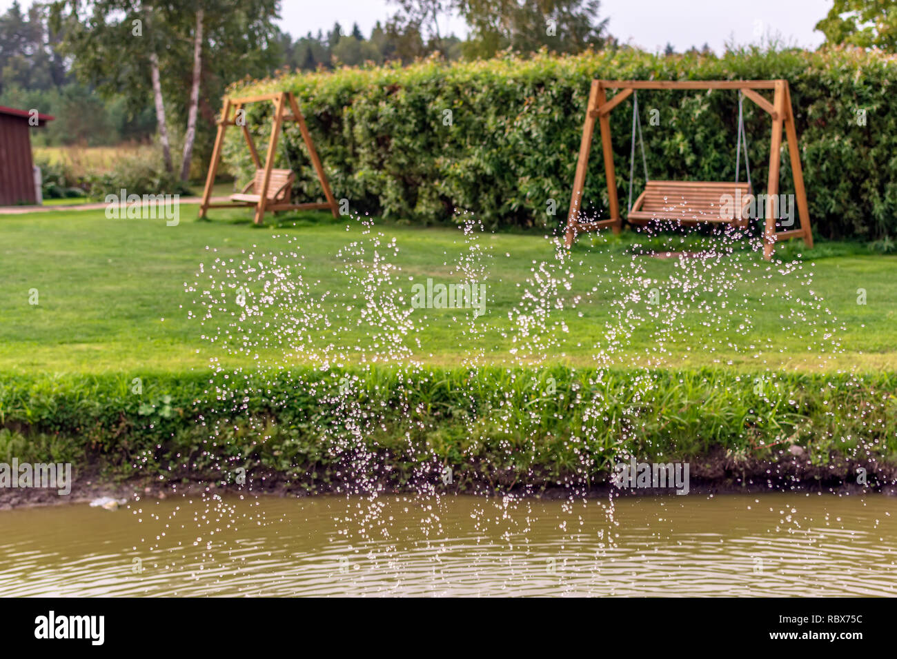 Two wooden swing benches in the garden with water drops in the ...