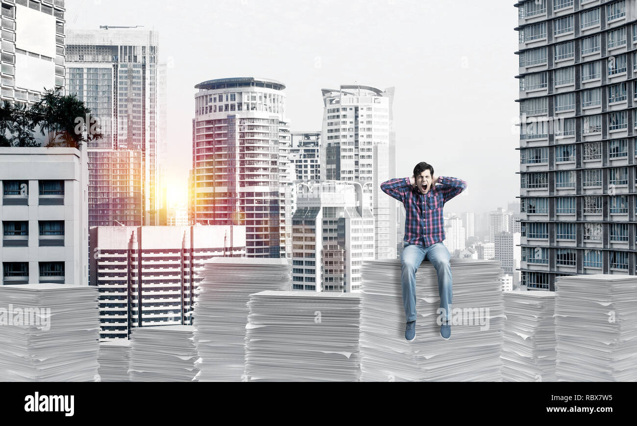 Attractive man sitting on pile of paper documents Stock Photo - Alamy
