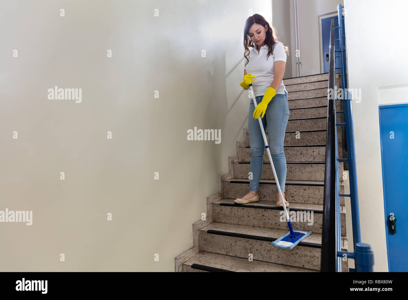 Young Female Janitor Cleaning Staircase With Mop Stock Photo - Alamy