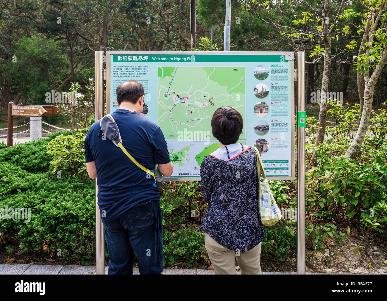 Tourists looking at a Visitor information board map at Ngong Ping ...