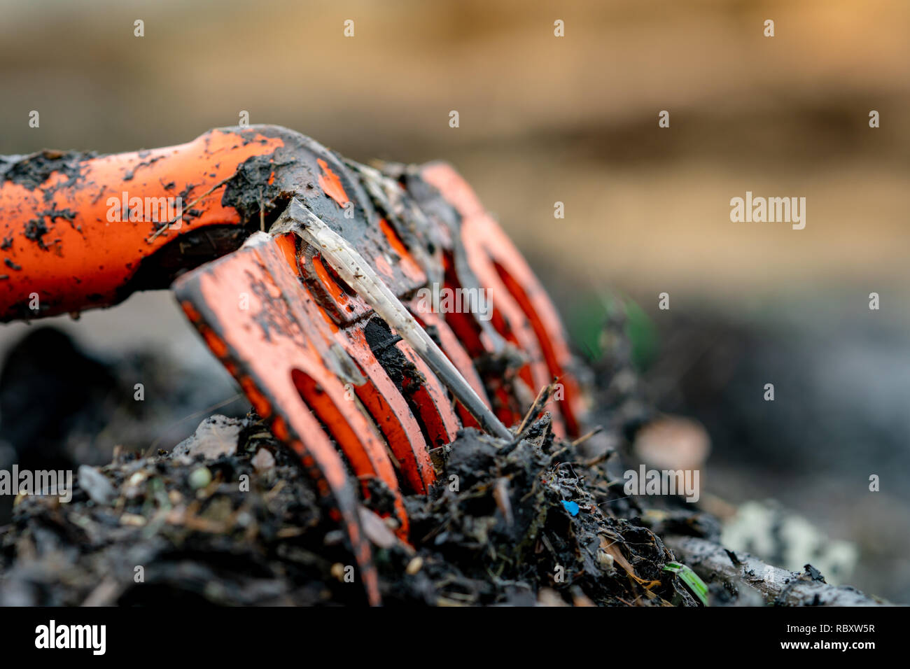 Closeup orange rake on pile of dirty plastic waste on blurred ...