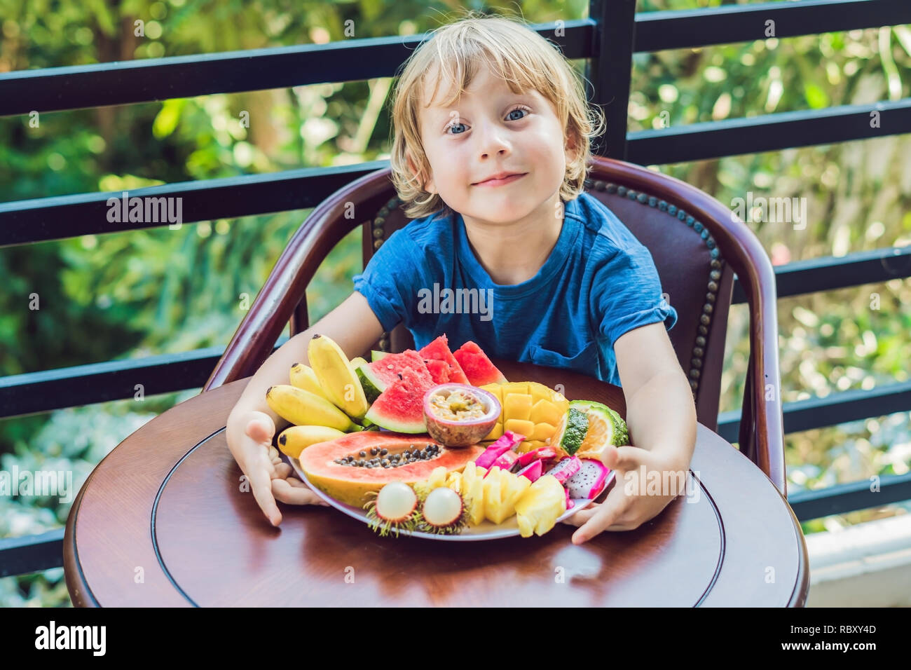 The boy is eating different fruits on the terrace Stock Photo - Alamy