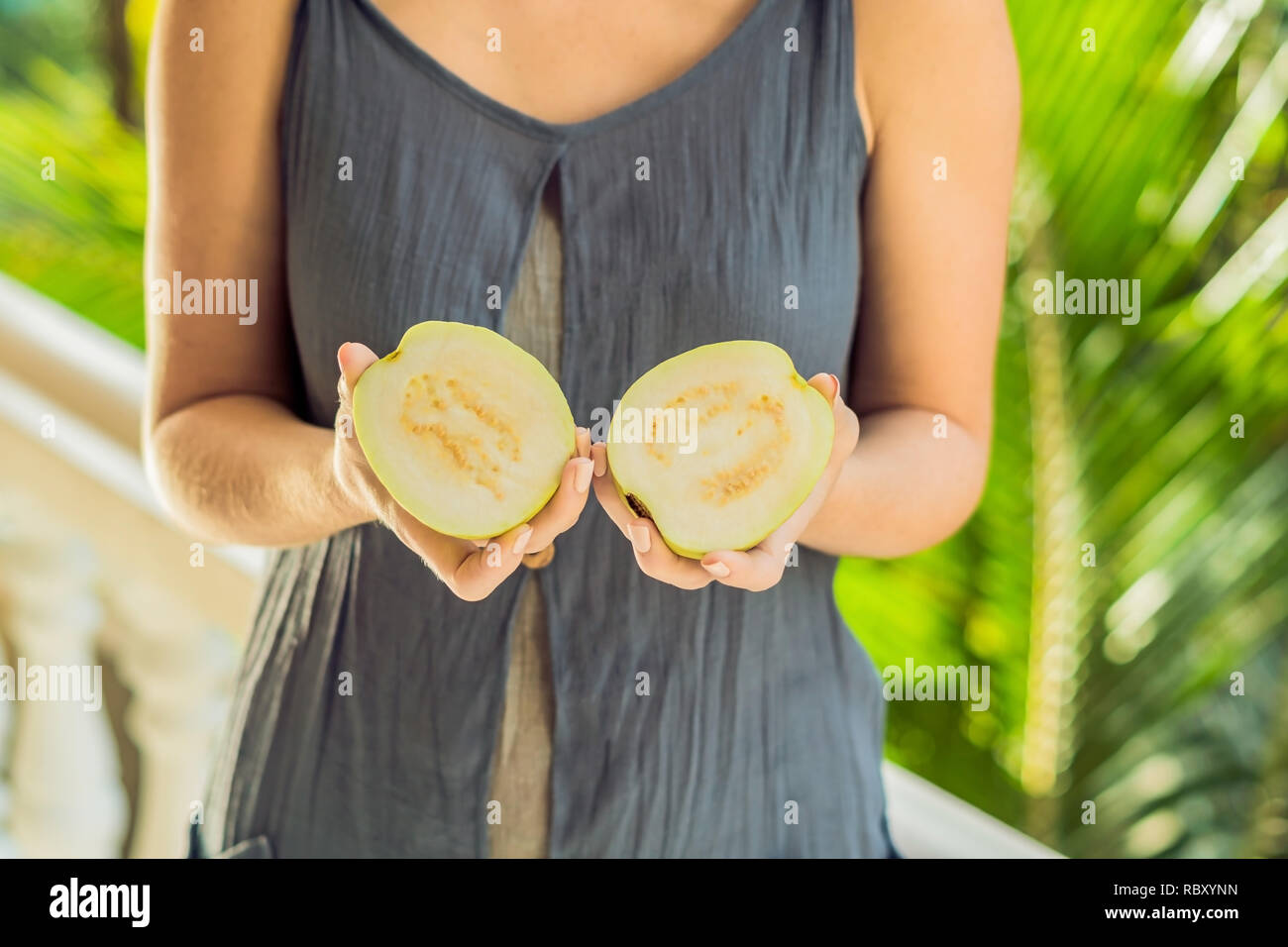 guava in beautiful female hands on a green background Stock Photo - Alamy