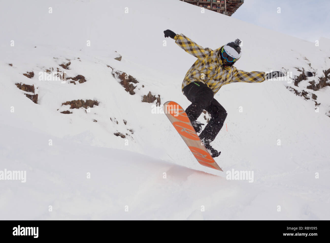 Snowboarder boy jumping into the air off slope having fun at holiday ...
