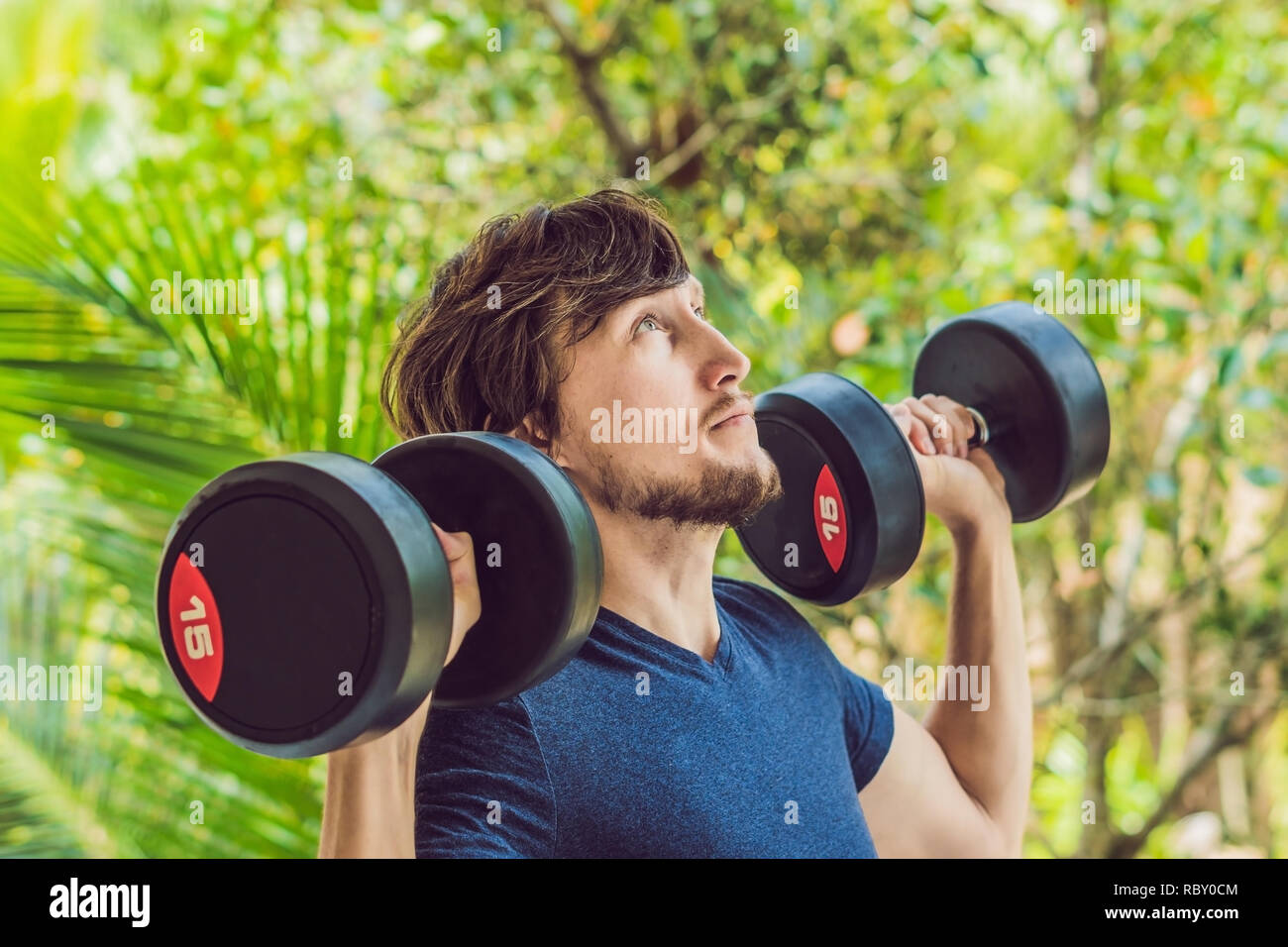 Training fitness man outside working out arms lifting dumbbells doing ...