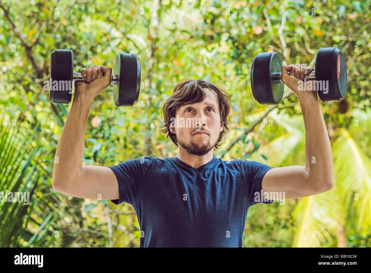 Training fitness man outside working out arms lifting dumbbells doing ...