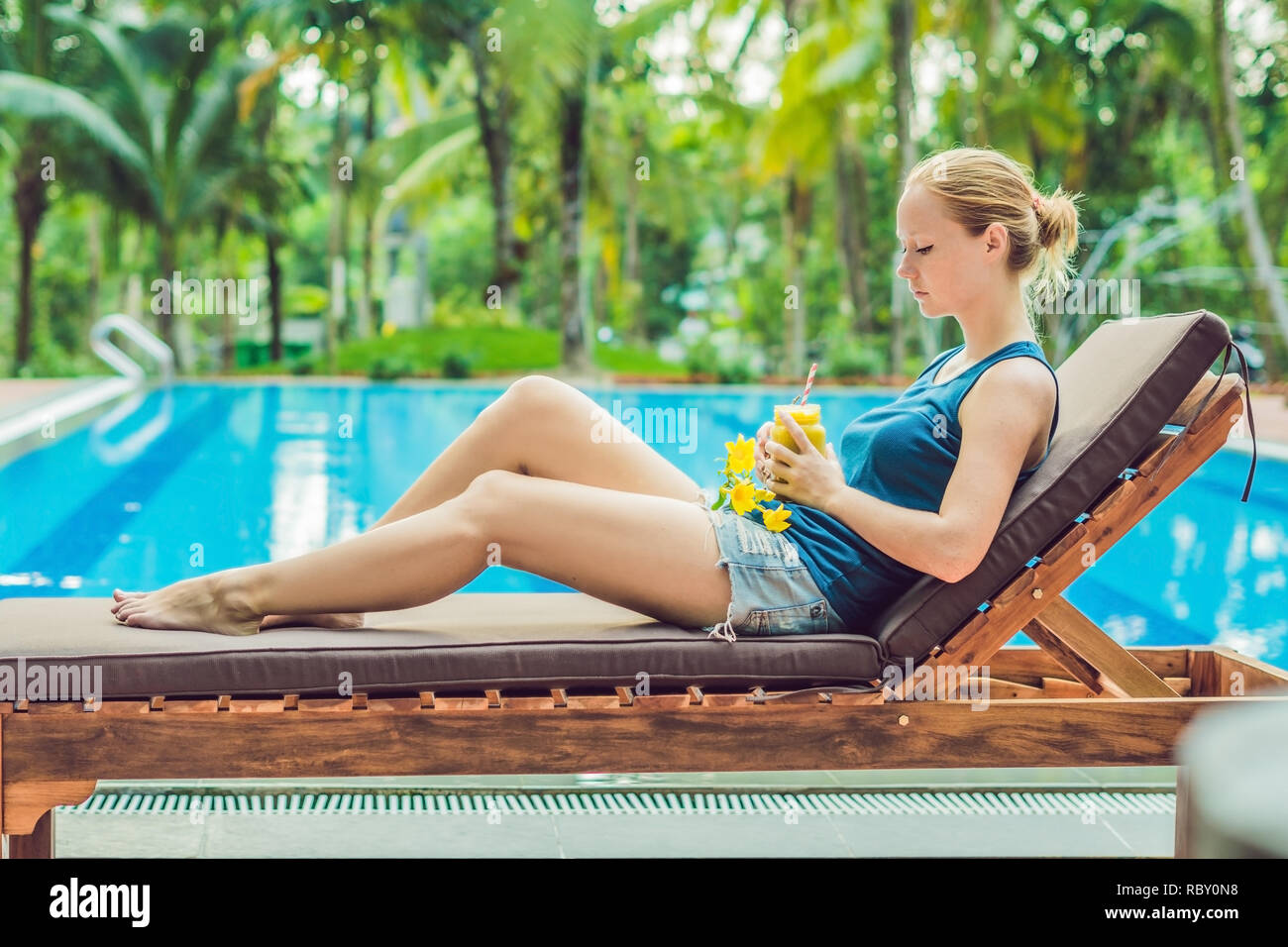 Young woman is holding a smoothie of mango on the background of the ...