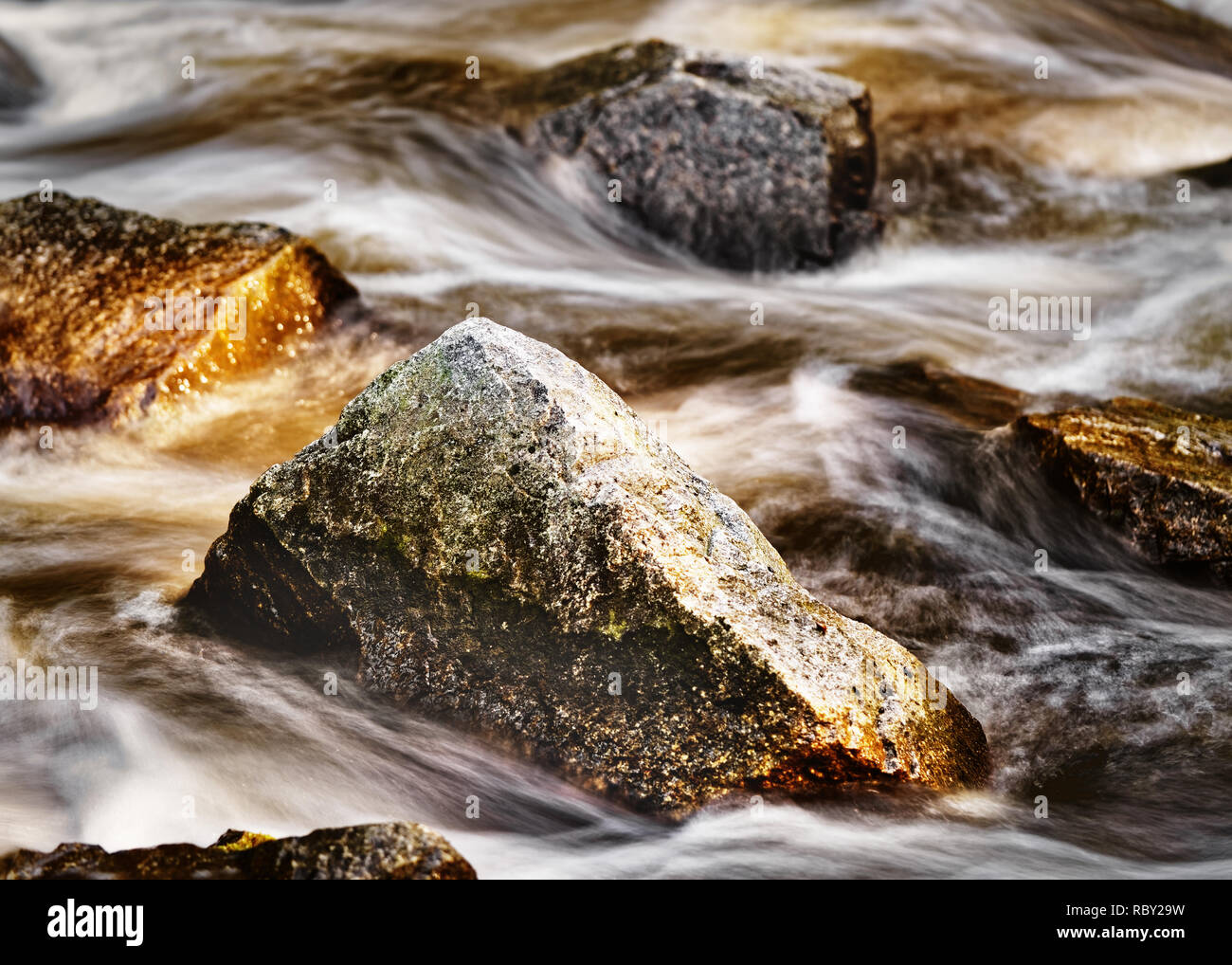 Large stones in the flowing water at evening light, water movement in ...