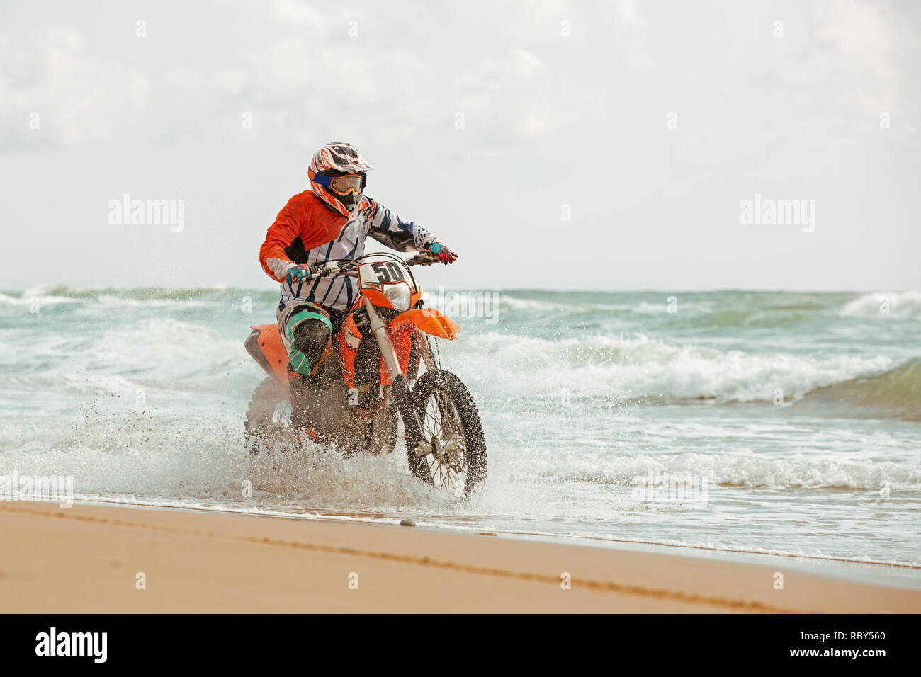 Motorcyclist in a protective suit rides a motorcycle on the sea ...
