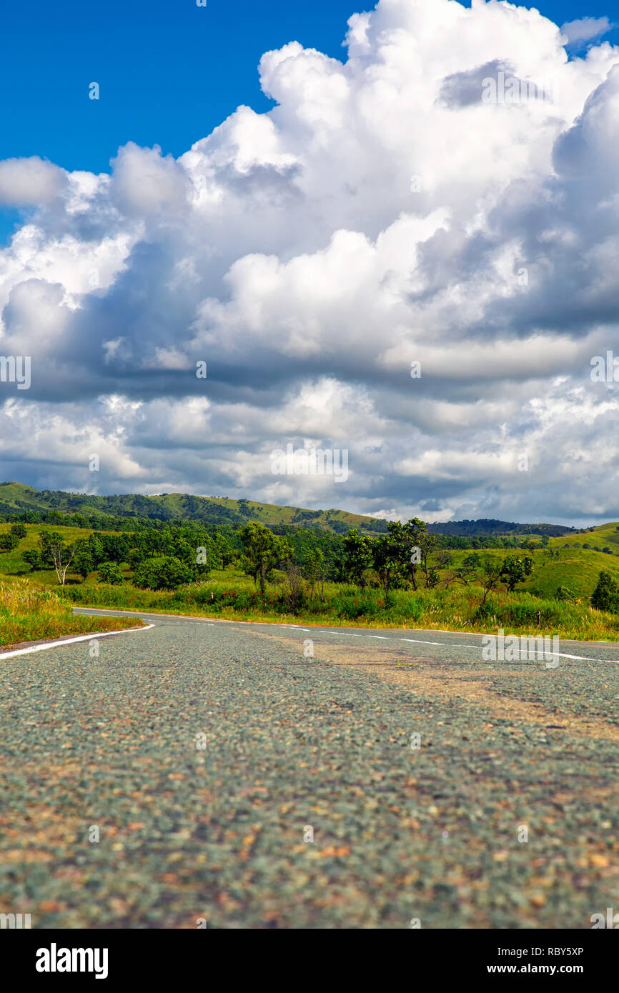 Winding country road and cloudy blue sky Stock Photo - Alamy
