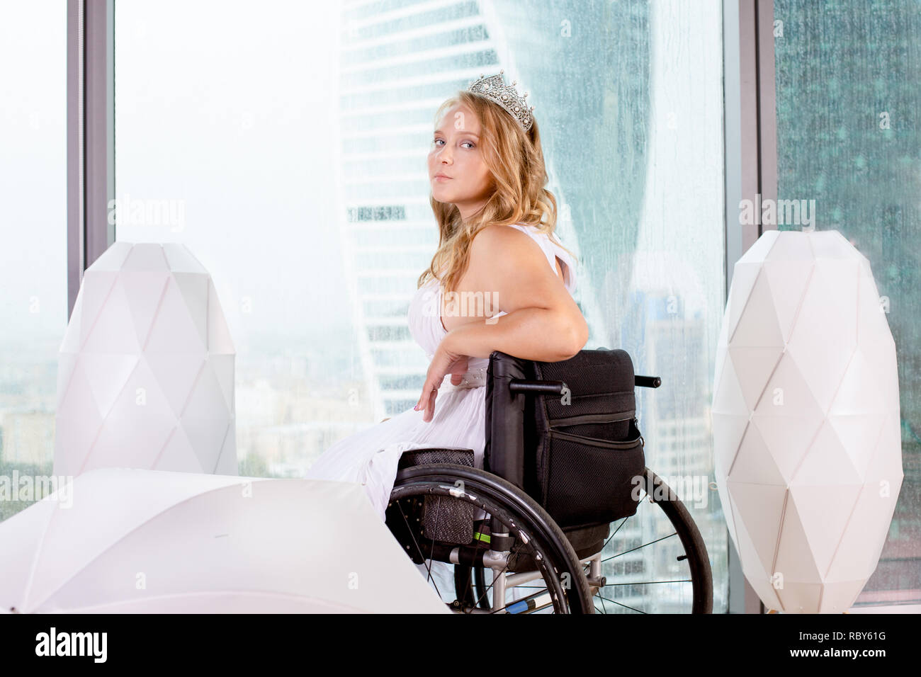 Beautiful disabled bride posing in a wheelchair against the background ...