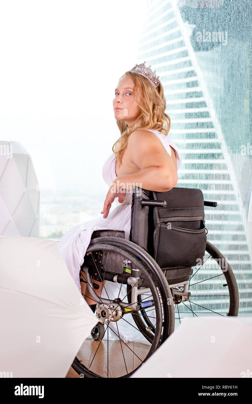Beautiful disabled bride posing in a wheelchair against the background ...
