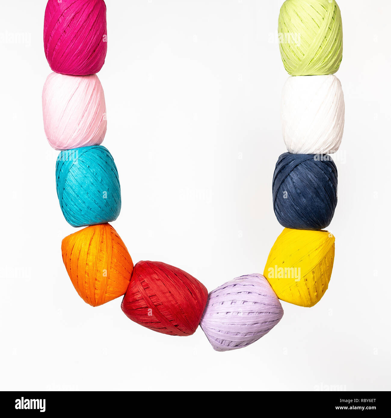 some colored raffia balls hanging from a white surface Stock Photo - Alamy