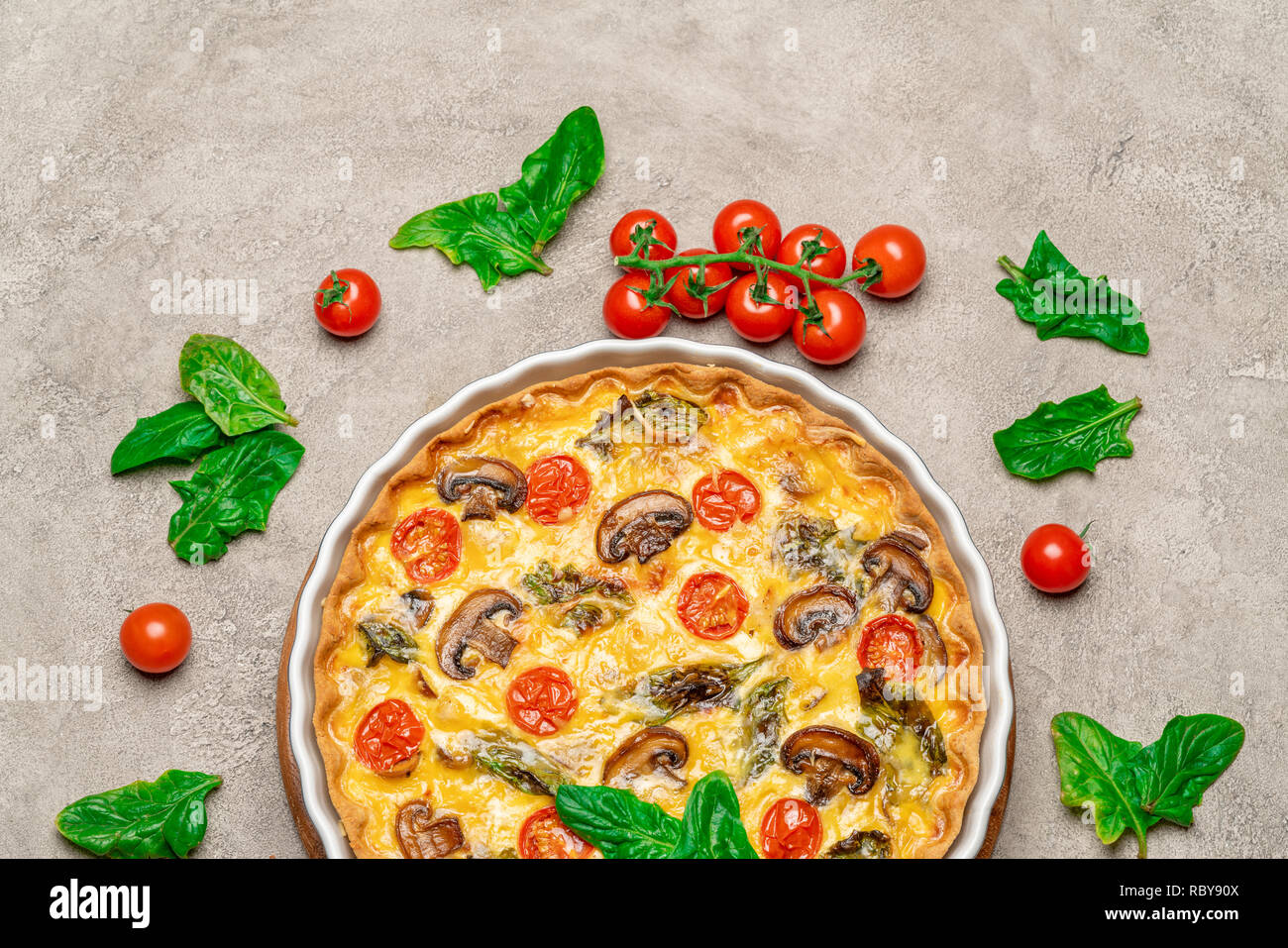 Baked homemade quiche pie in ceramic baking form on concrete background ...