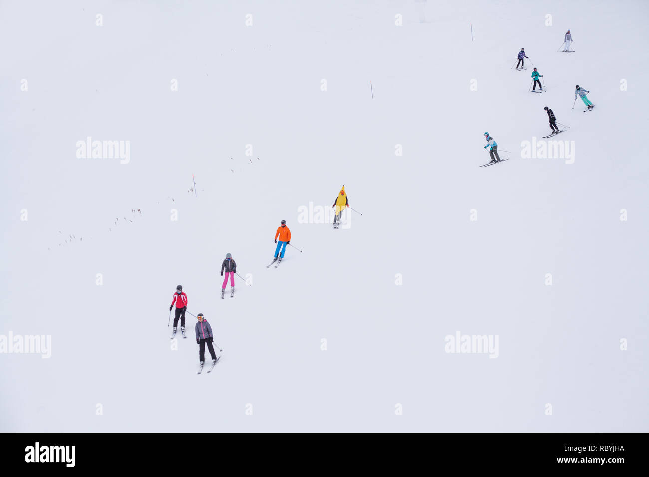 Line of skiers following each other downhill in a curve Stock Photo - Alamy