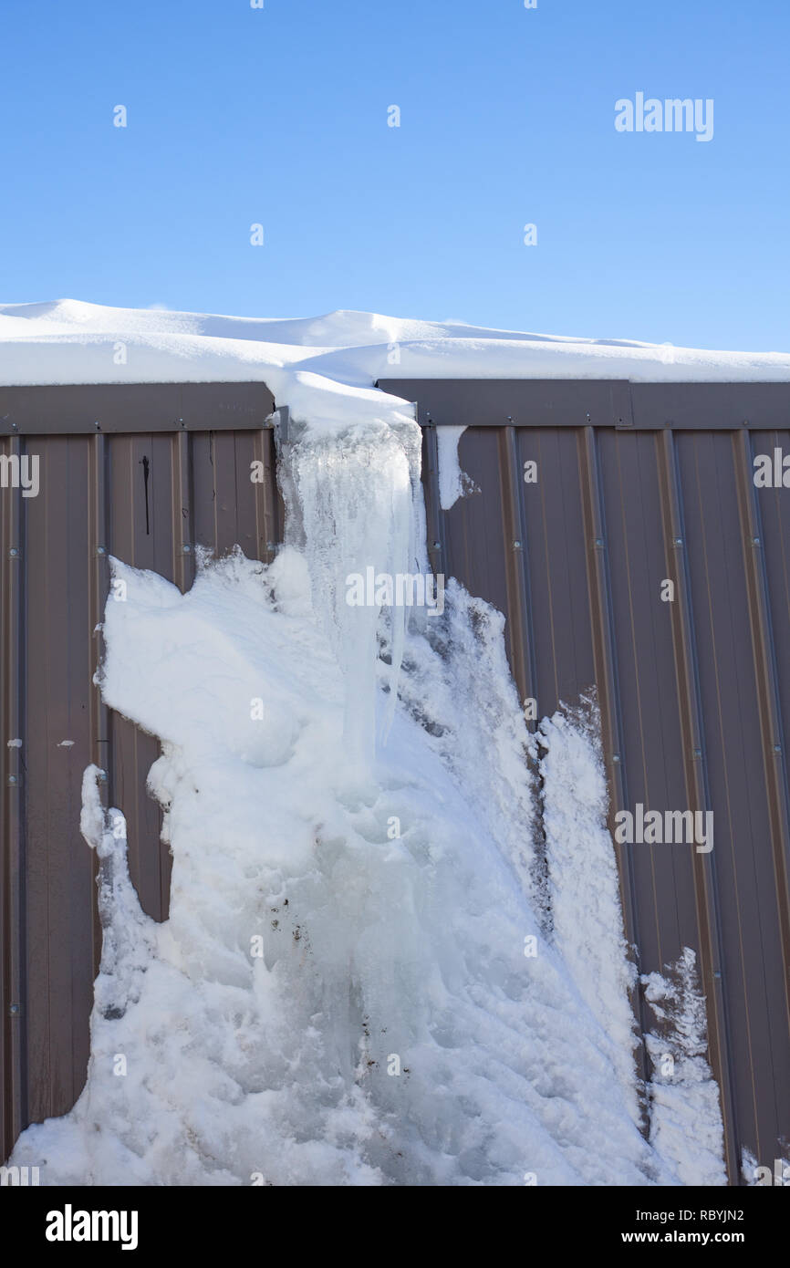 Ice falling from roof of warehouse with blue sky above Stock Photo - Alamy