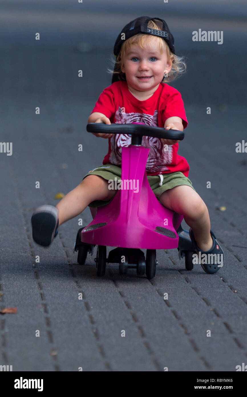 A photo of a happy kid driving with a purple plasma car like ride on ...