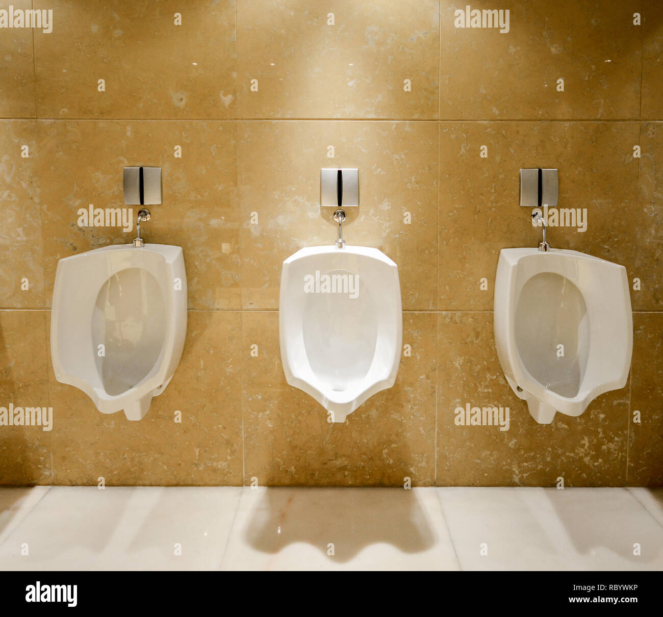 A row of urinals in tiled wall in a public luxurious restroom Stock ...