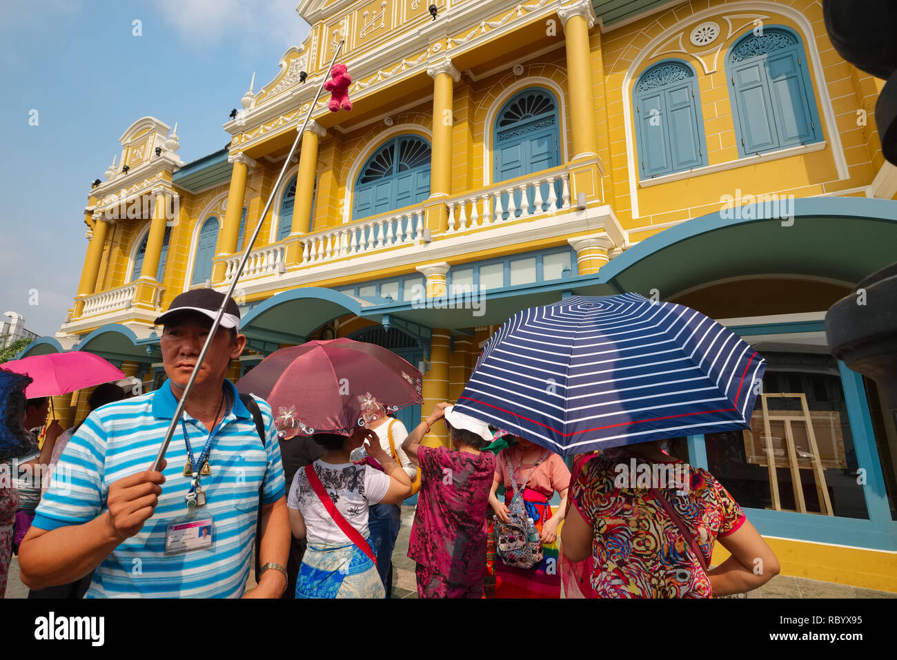 A Chinese tour guide in front of a colonial-style building in Bangkok ...