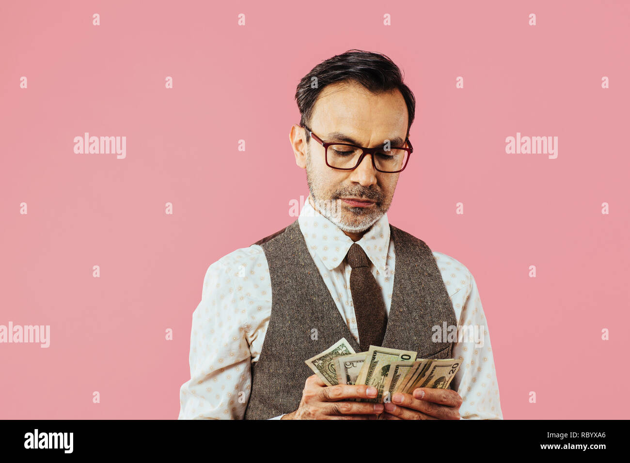 Mature man counting money, isolated on pink studio background Stock ...