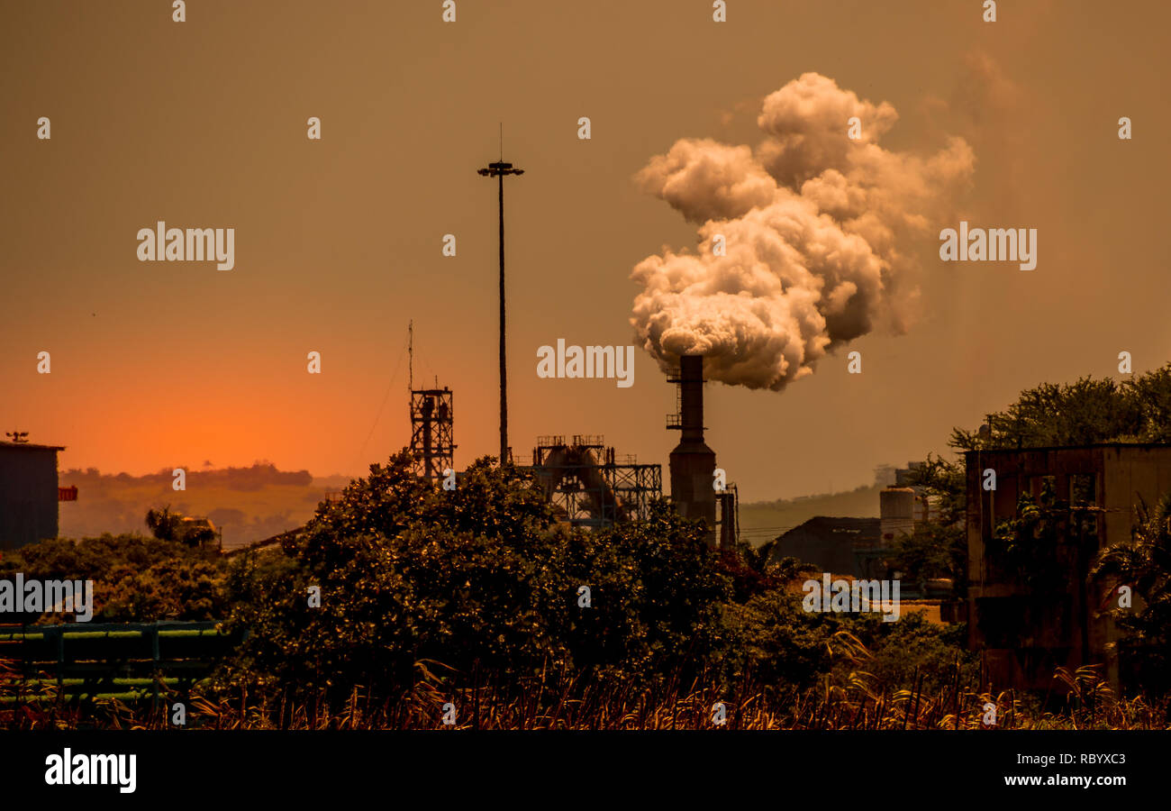 A chimney at an industrial plant spews smoke into the evening air image ...