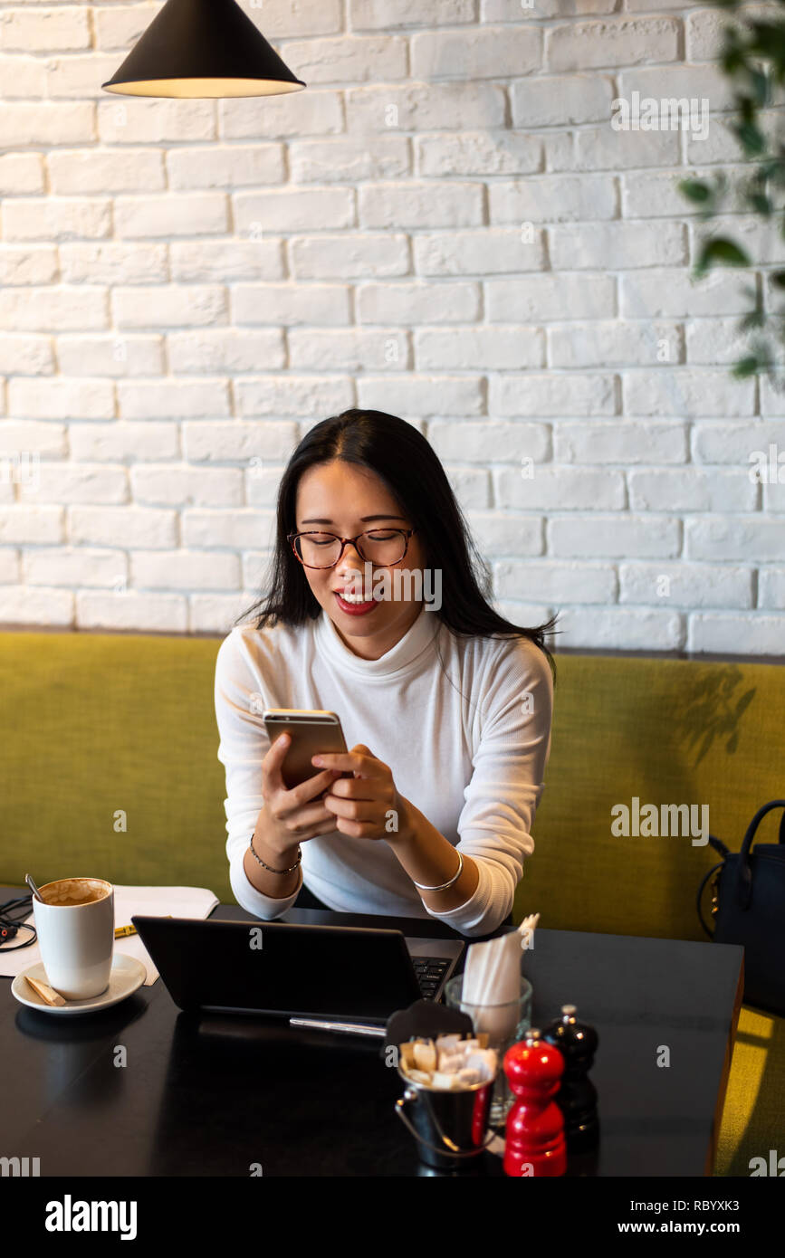 Girl using phone while working in a coffee bar Stock Photo - Alamy