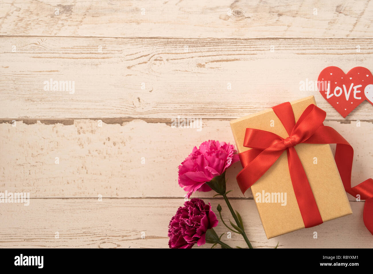Kraft gift box with red ribbon bow and carnation, concept of giving ...
