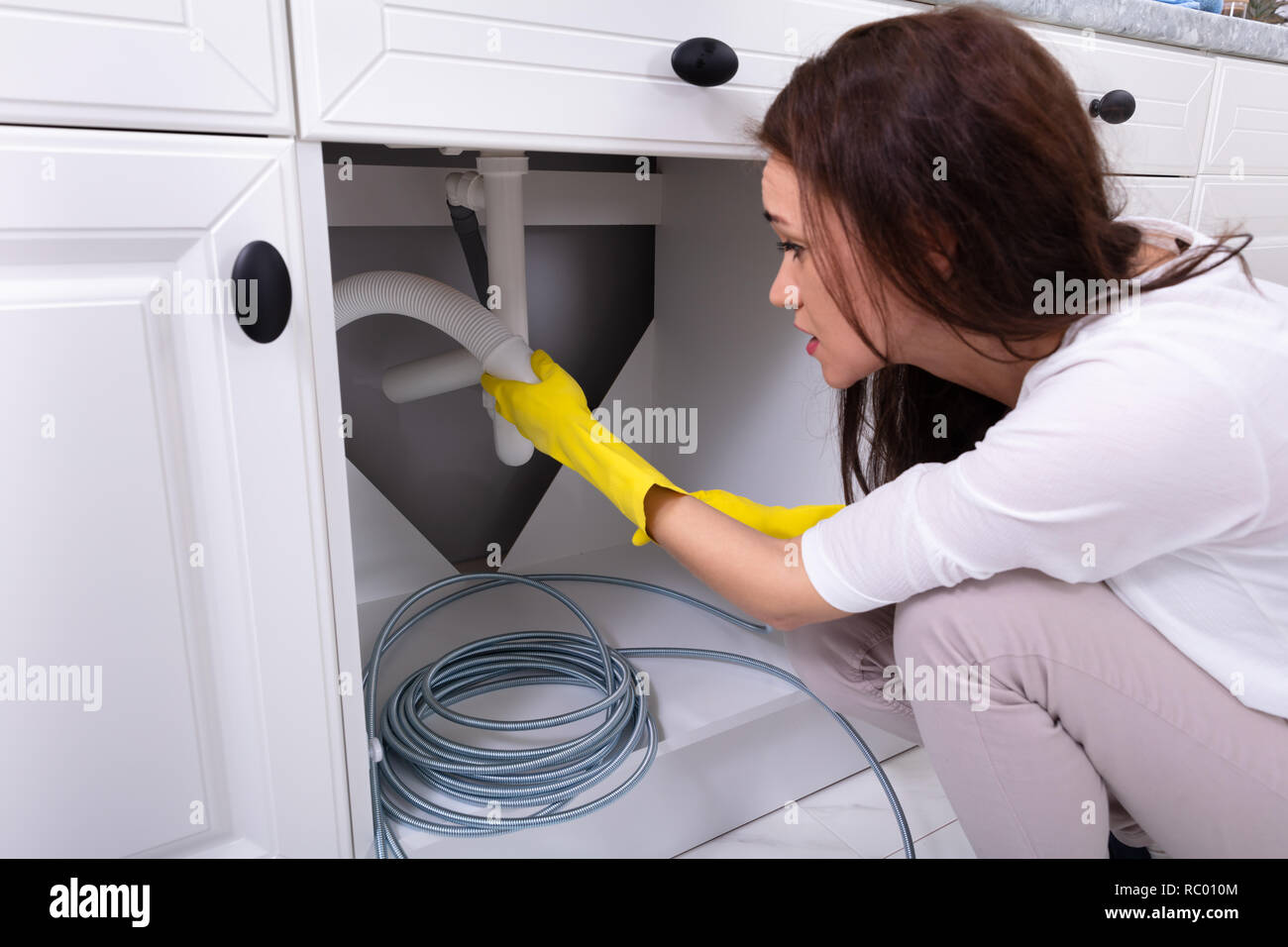 Side View Of A Young Woman Cleaning Clogged Sink Pipe In Kitchen Stock ...