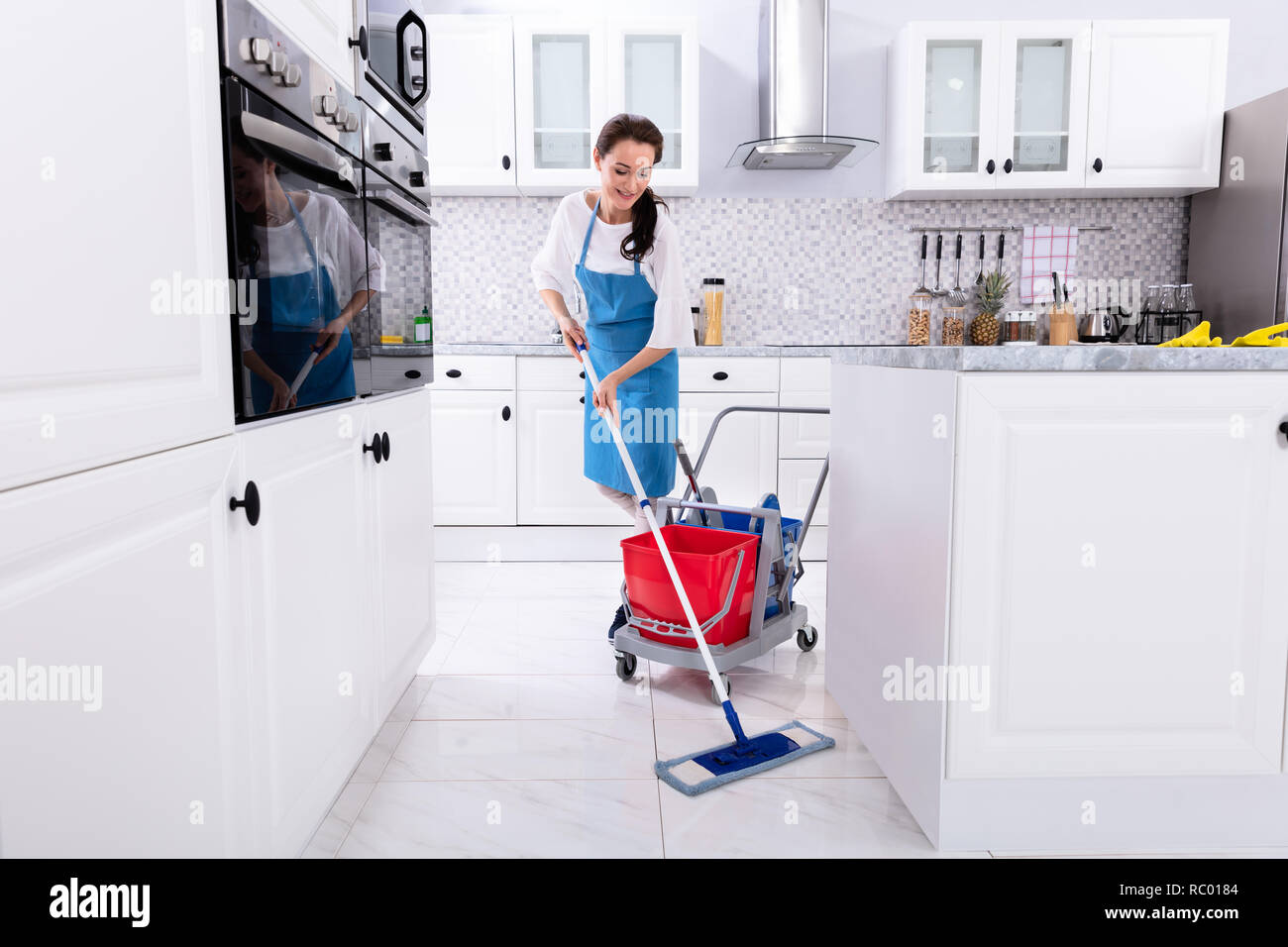 Happy Female Janitor Cleaning Floor With Mop In Kitchen Stock Photo - Alamy