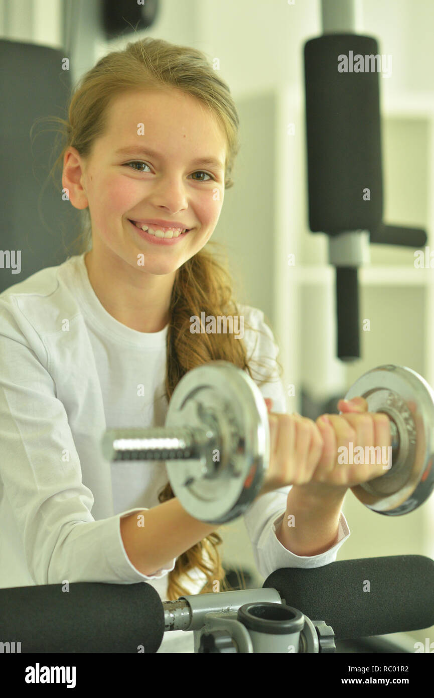 Portrait of little girl doing exercises with dumbbell in gym Stock ...