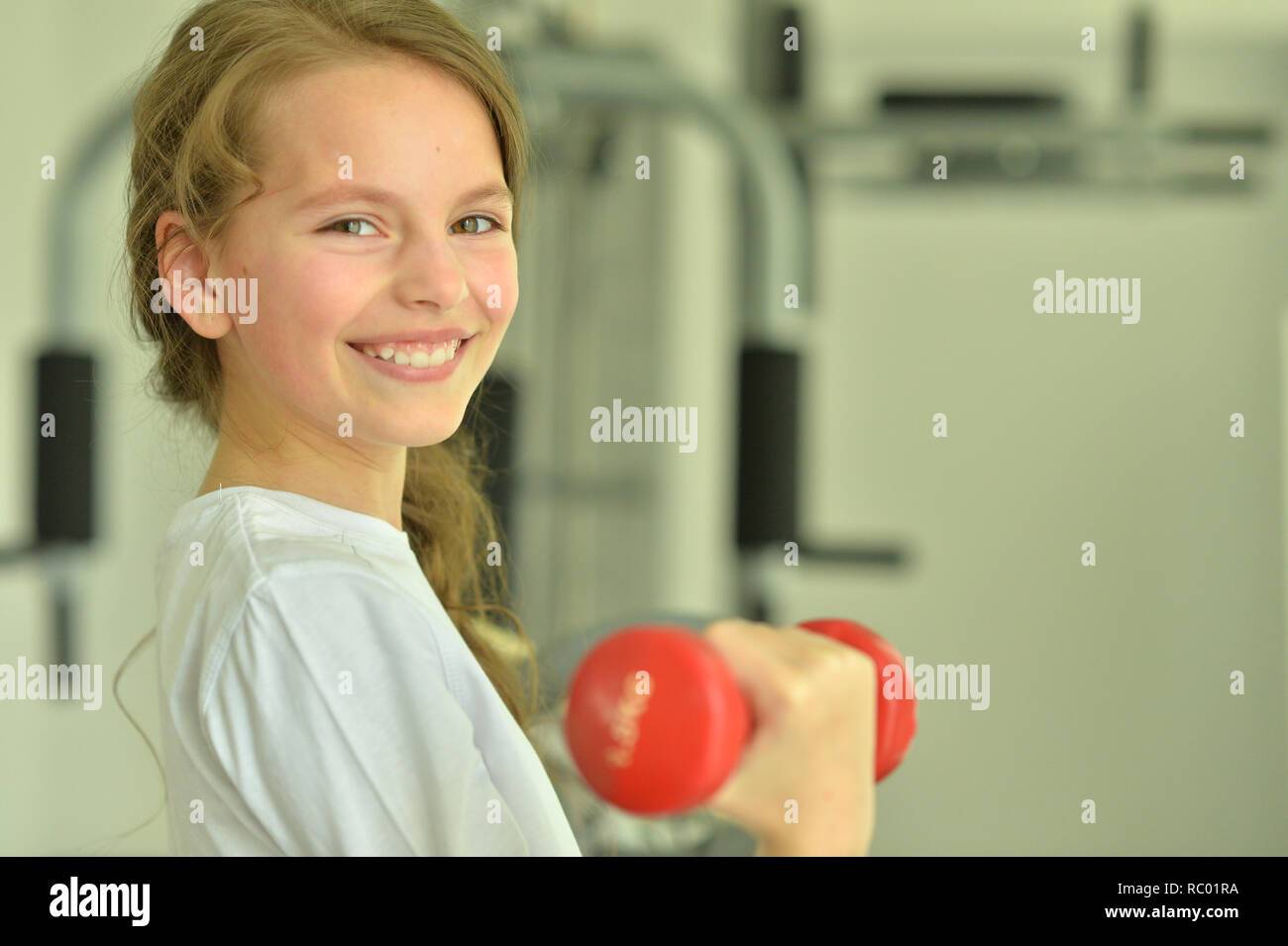 Portrait of little girl doing exercises with dumbbell in gym Stock ...