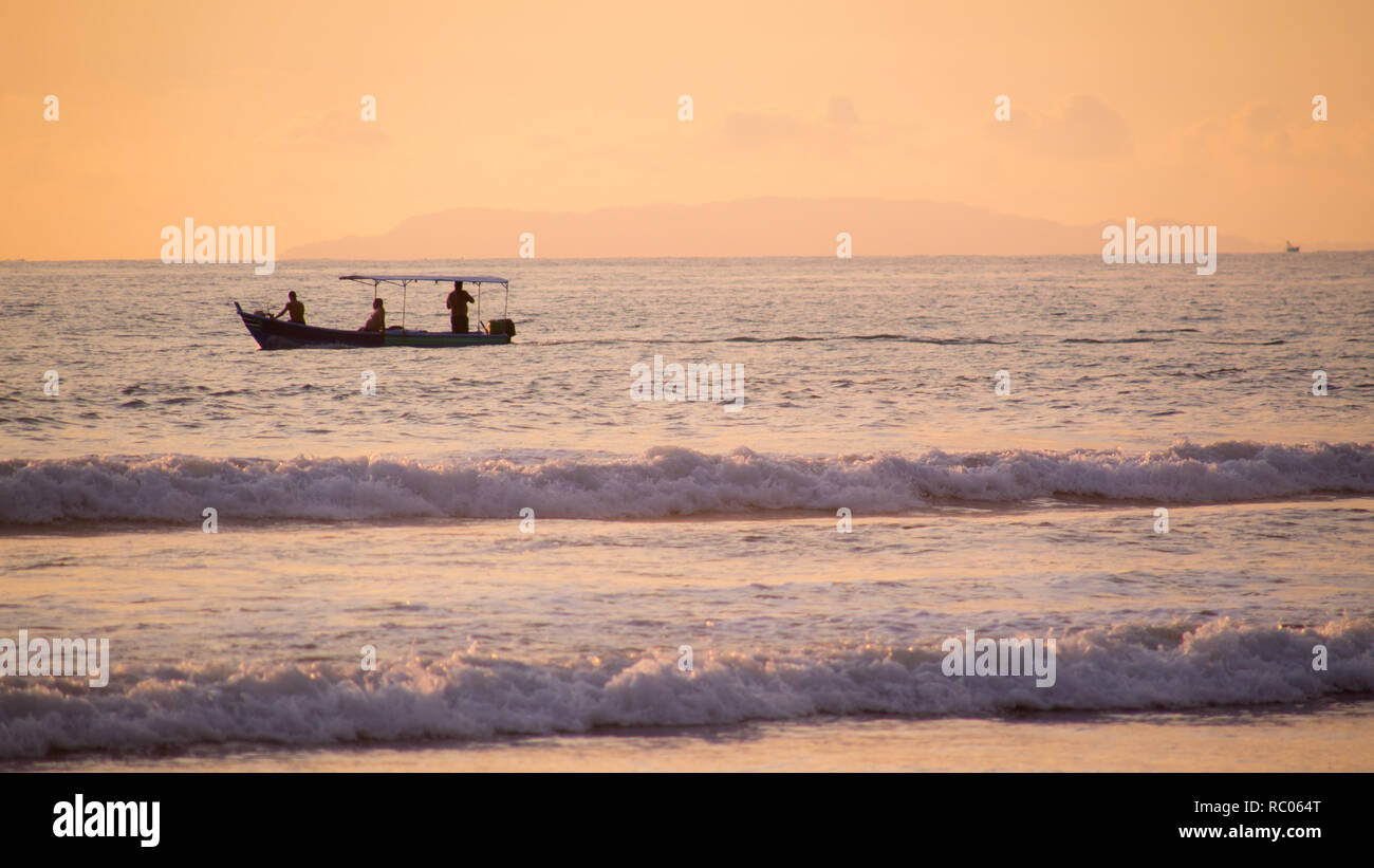 A photo of a boat on the sea on the background of an island silhouette ...