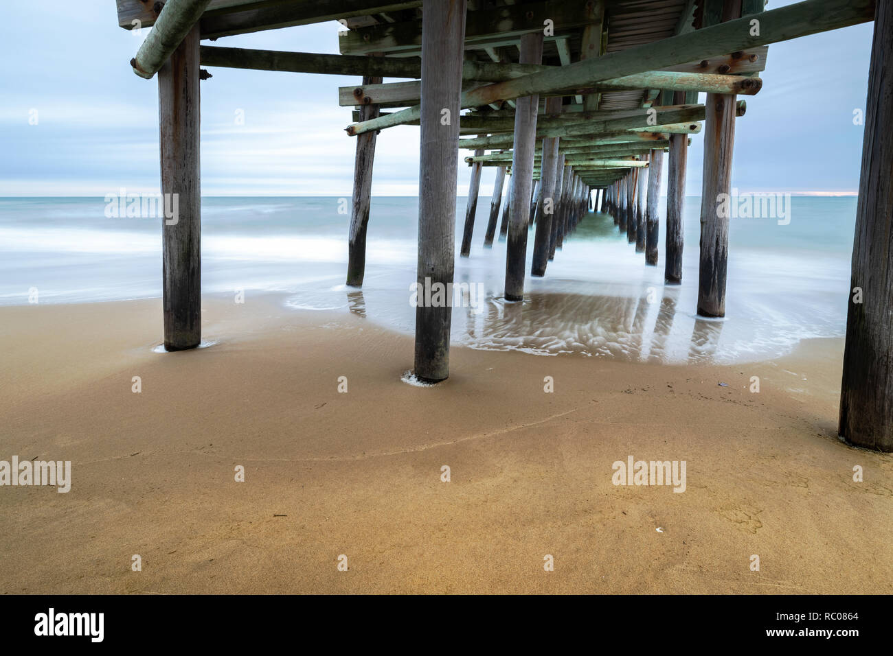 As the sun rises behind the Sandbridge Fishing Pier, the waves crash ...