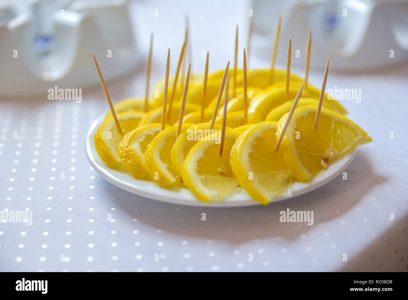 Yellow lemon slice standing on a white plat on blurred table Stock ...