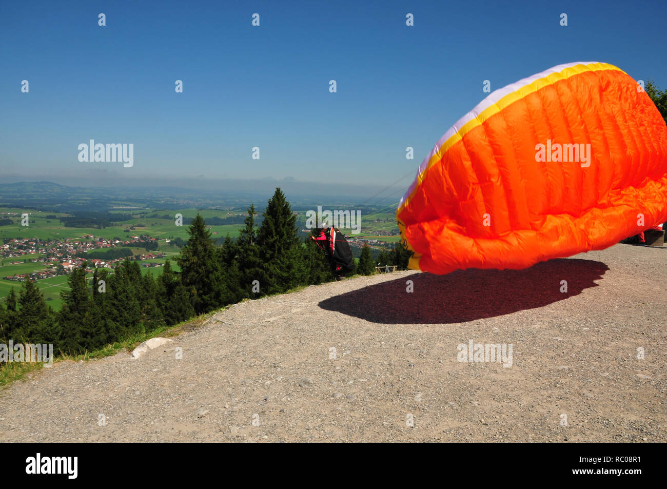 Paraglider gets ready for the jump with an orange parachute and a ...