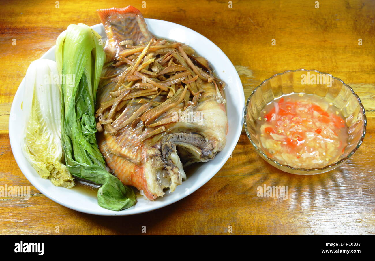 steamed red mango fish with vegetable topping slice ginger on plate ...