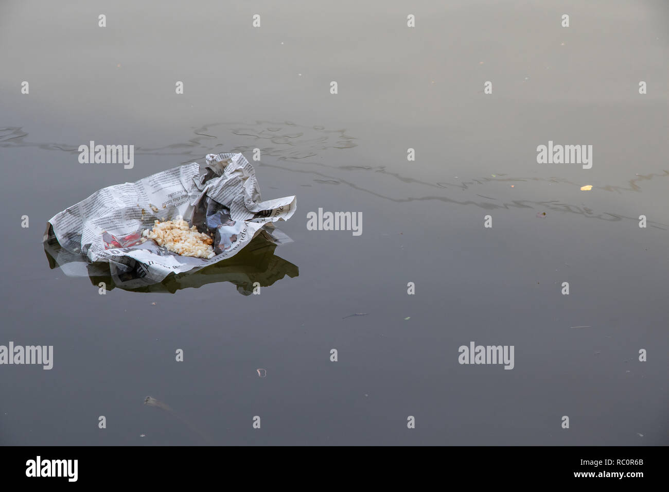 Spoiled food on newspapers floating in the waste water background Stock ...