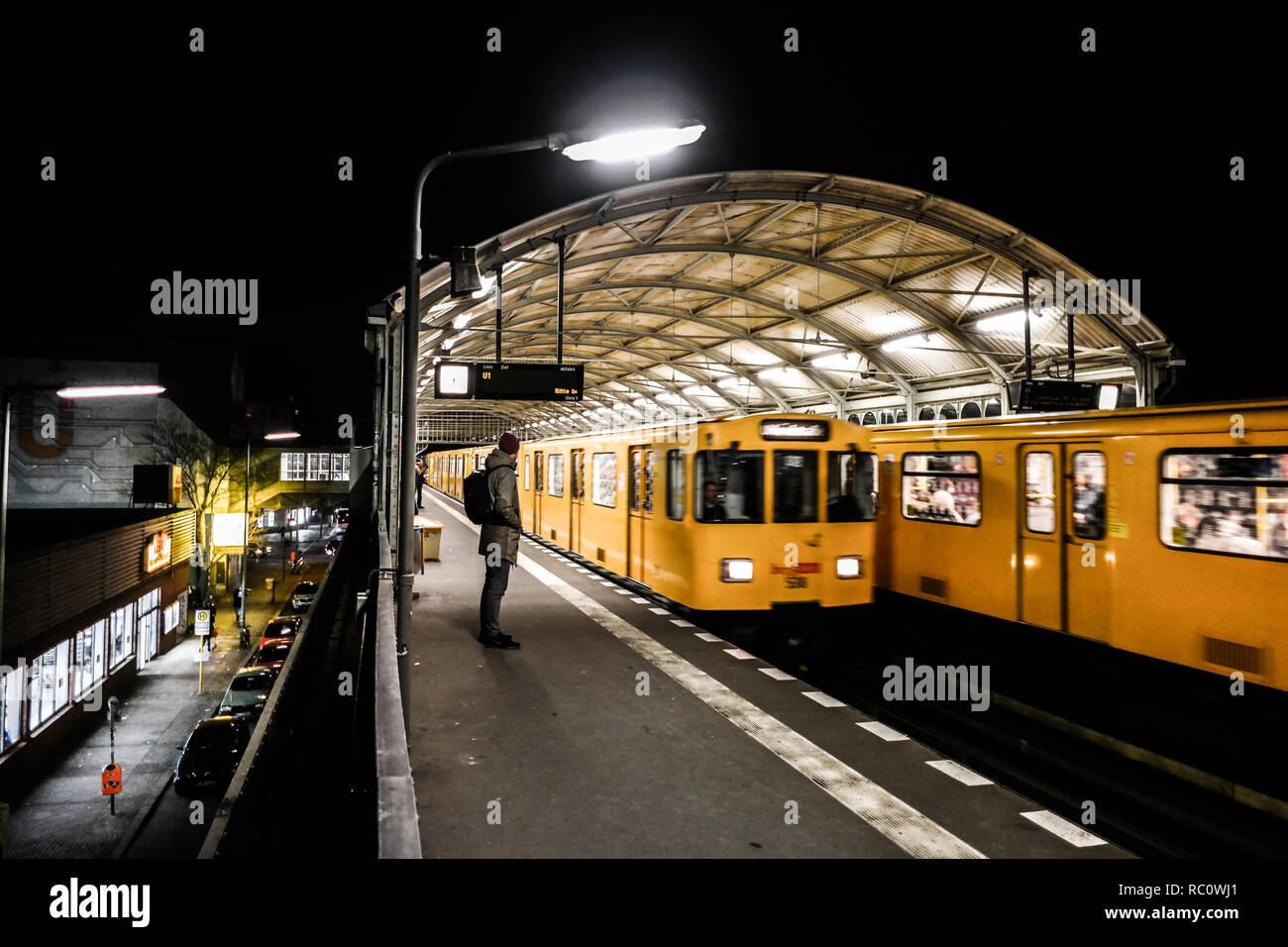 Atmospheric night scene of yellow U-Bahn train at overground station ...