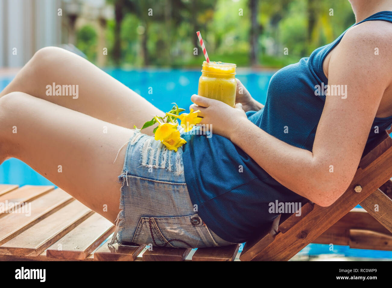 Young woman is holding a smoothie of mango on the background of the ...