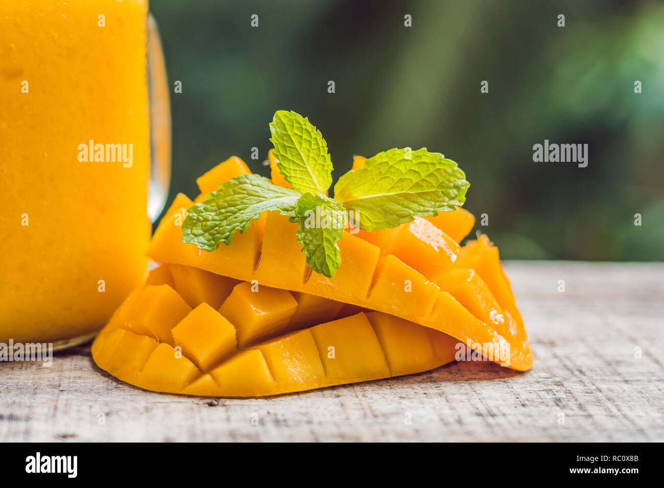 Mango smoothie in a glass Mason jar and mango on a green background ...
