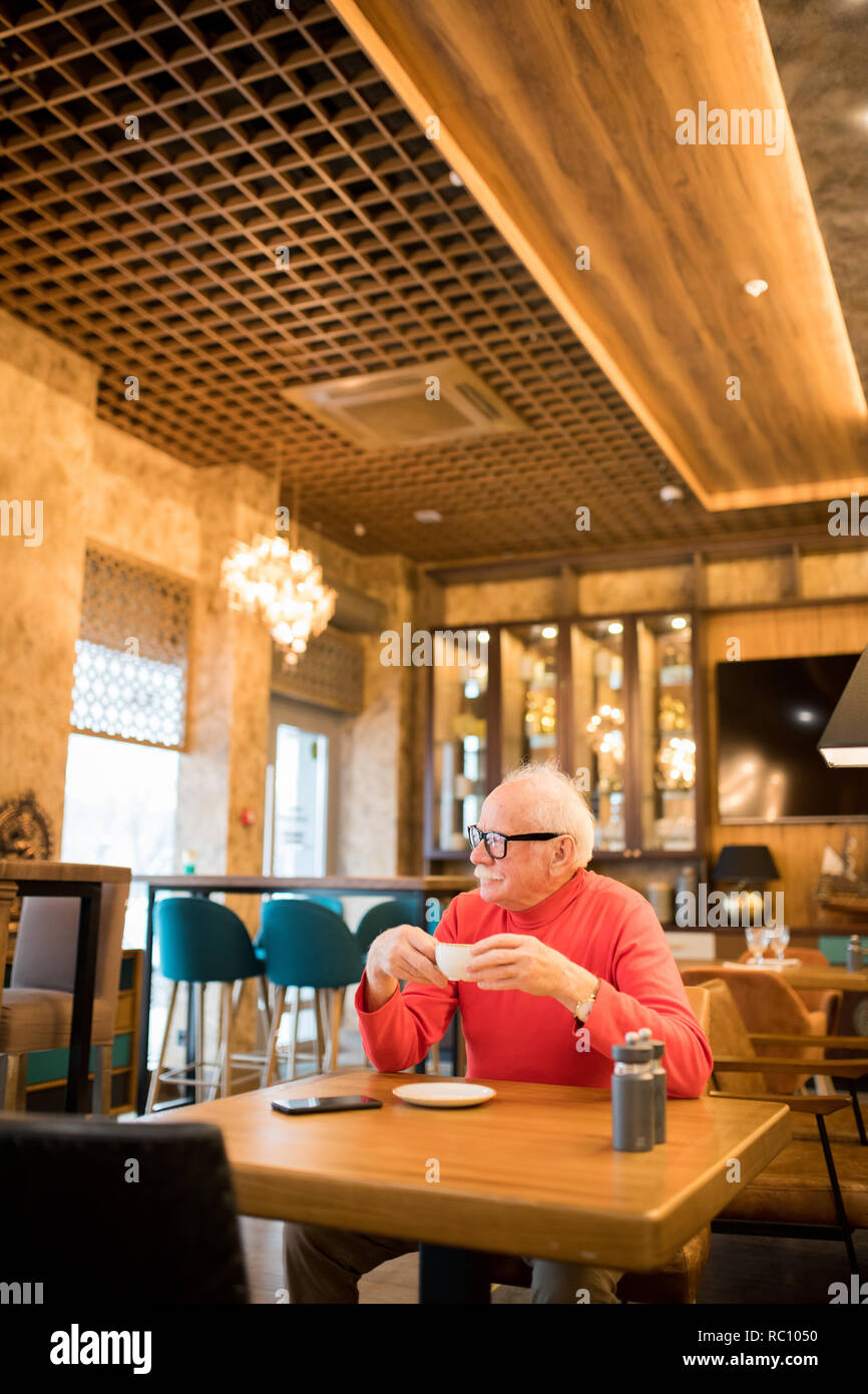 Introspective senior man contemplating in modern restaurant Stock Photo ...