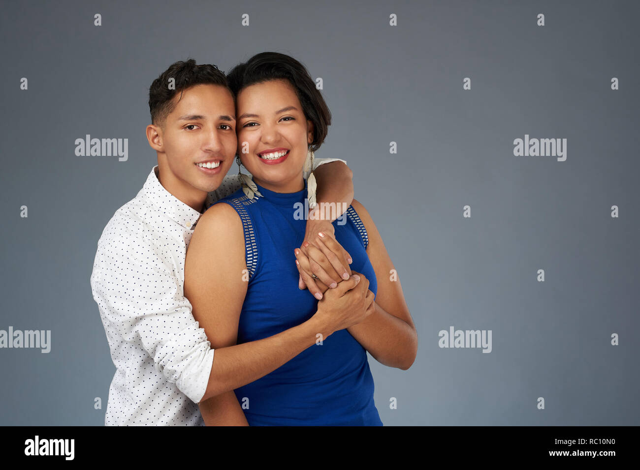 Portrait of happy young latin couple isolated on gray studio background ...