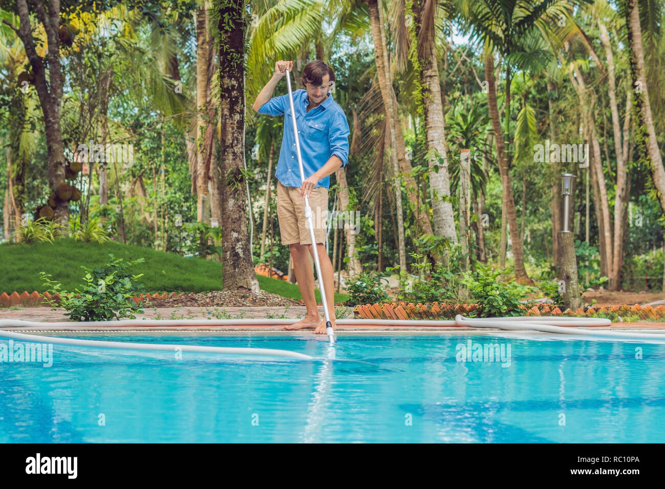 Cleaner of the swimming pool . Man in a blue shirt with cleaning ...