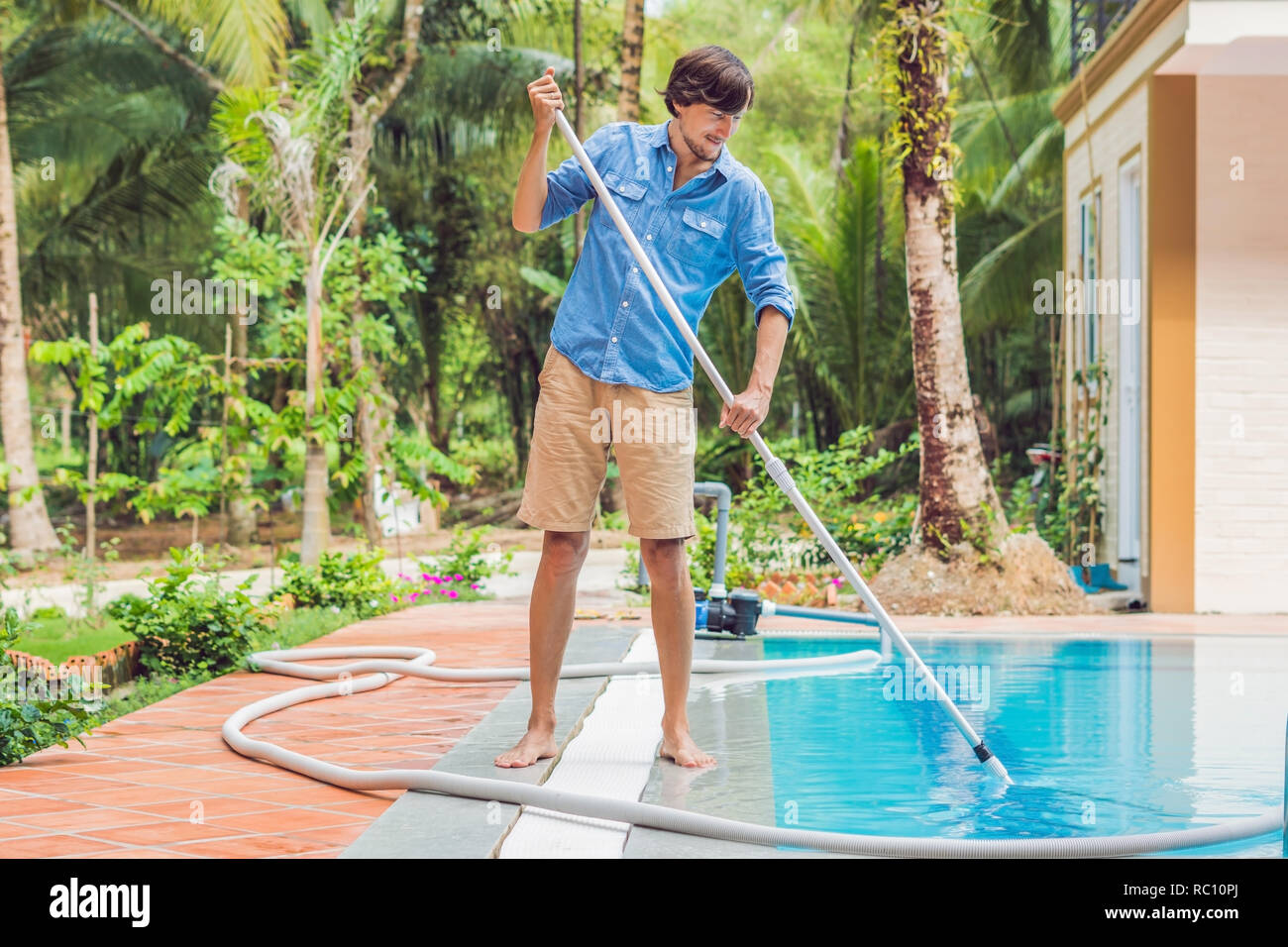 Cleaner of the swimming pool . Man in a blue shirt with cleaning ...
