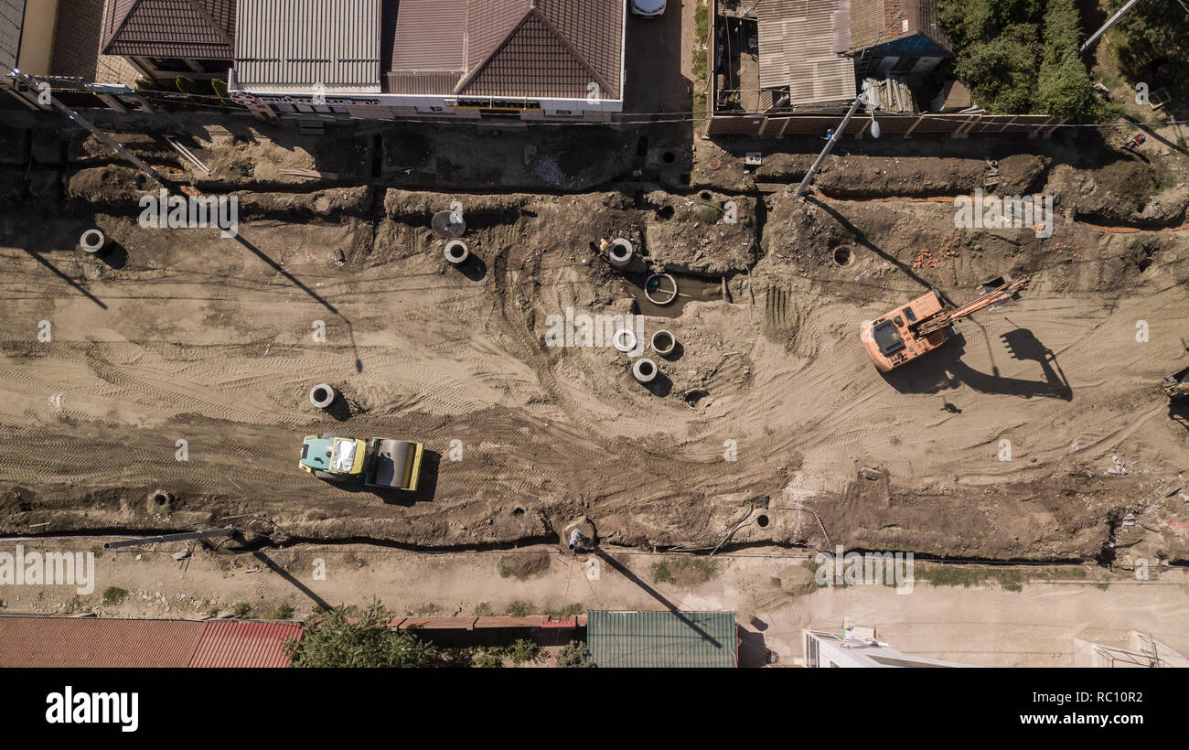 Heavy equipment is grading the land, moving and flattening out red clay ...