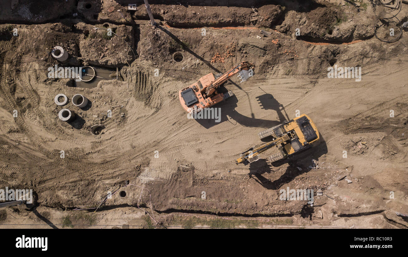 Heavy equipment is grading the land, moving and flattening out red clay ...